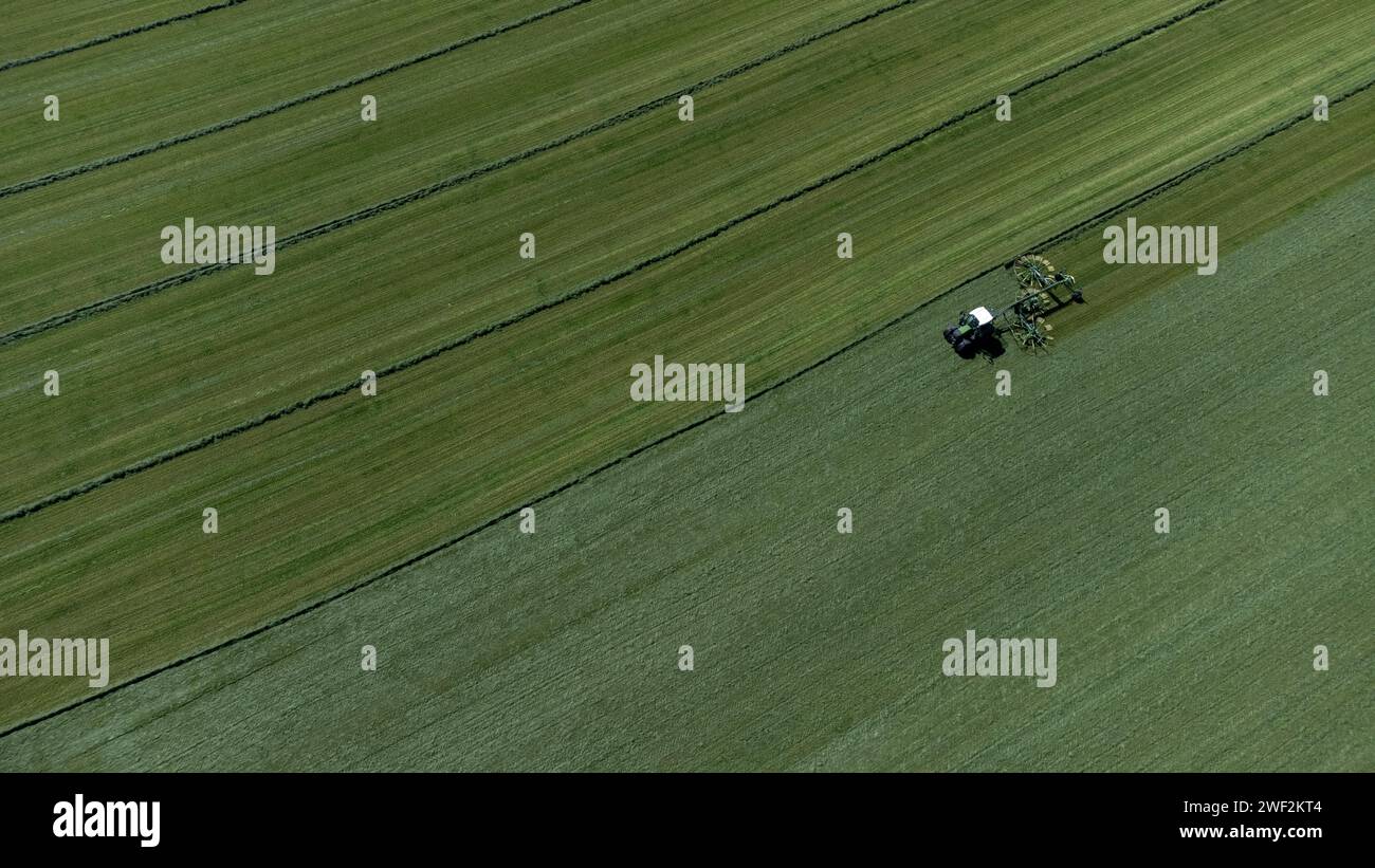 Farmer cutting grass to straight rows with tractor and large roundabout ...