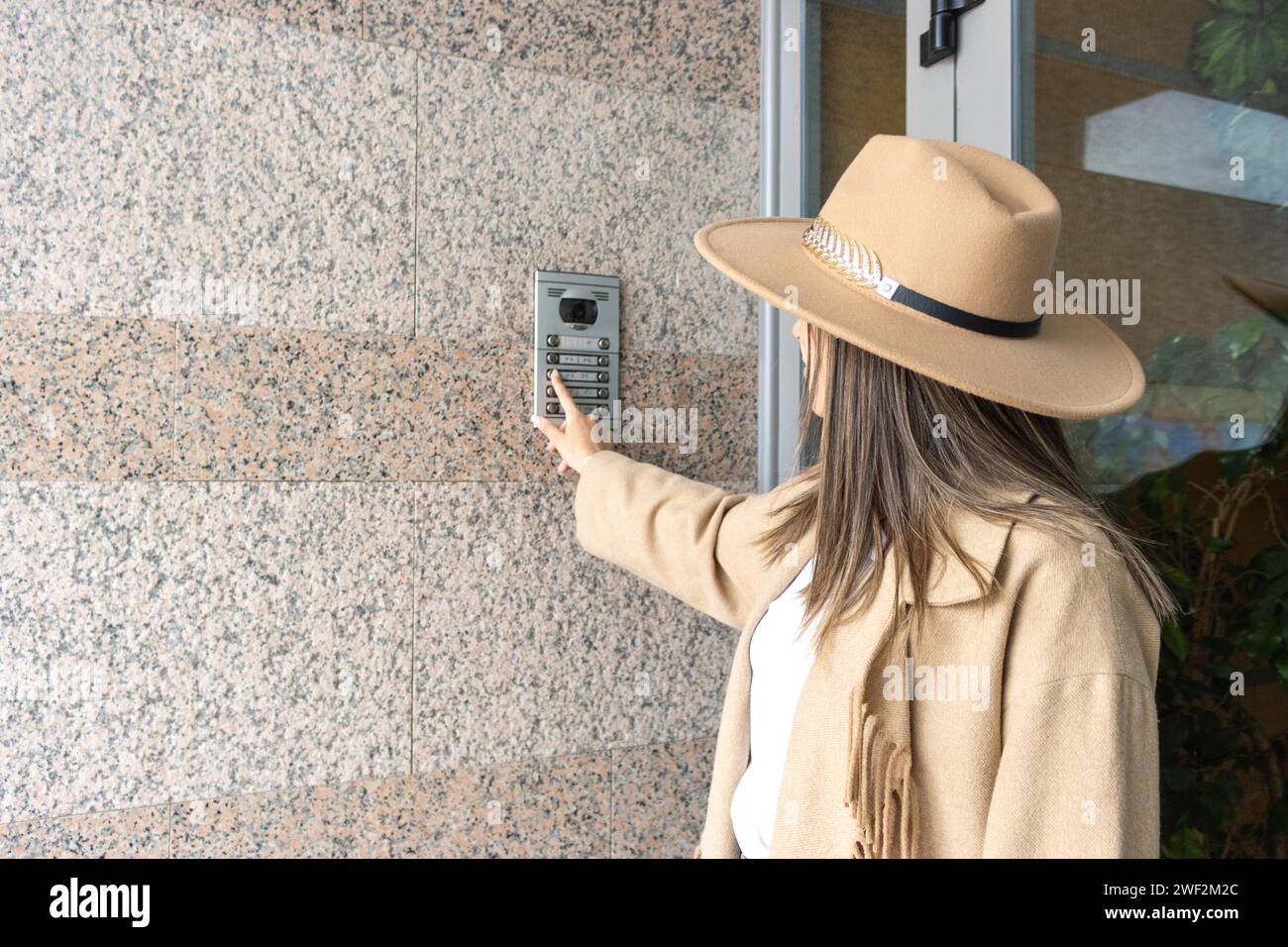 Side view of unrecognizable woman wearing a hat pushing the button of ...
