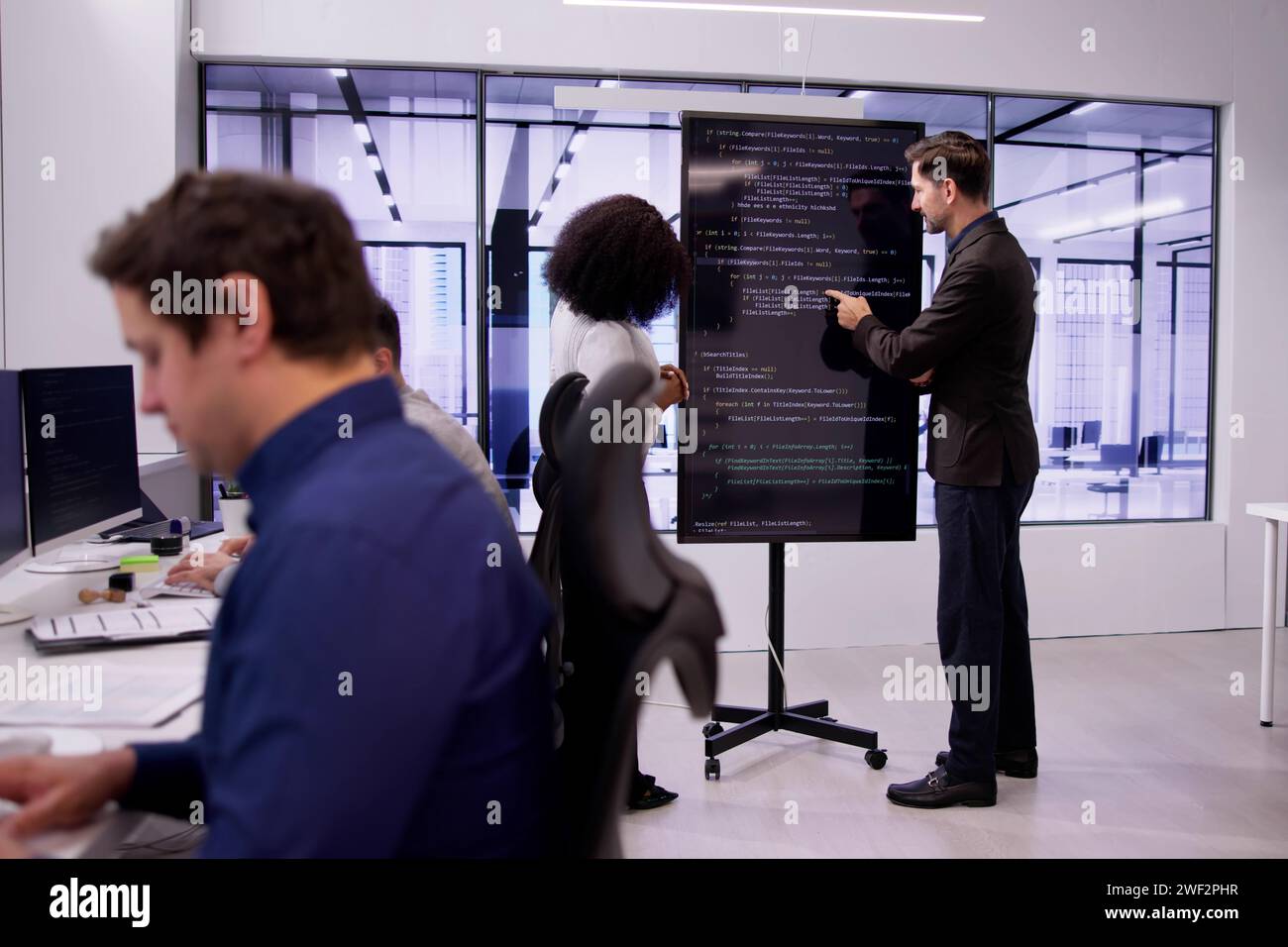 Programmer Team Meeting With TV Screen In Office. Diverse Developers ...