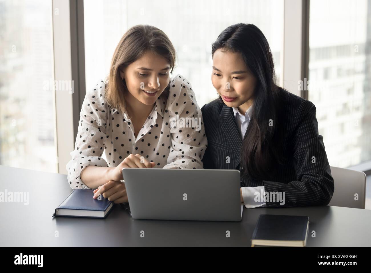 Two positive diverse young colleague girls talking at workplace Stock ...