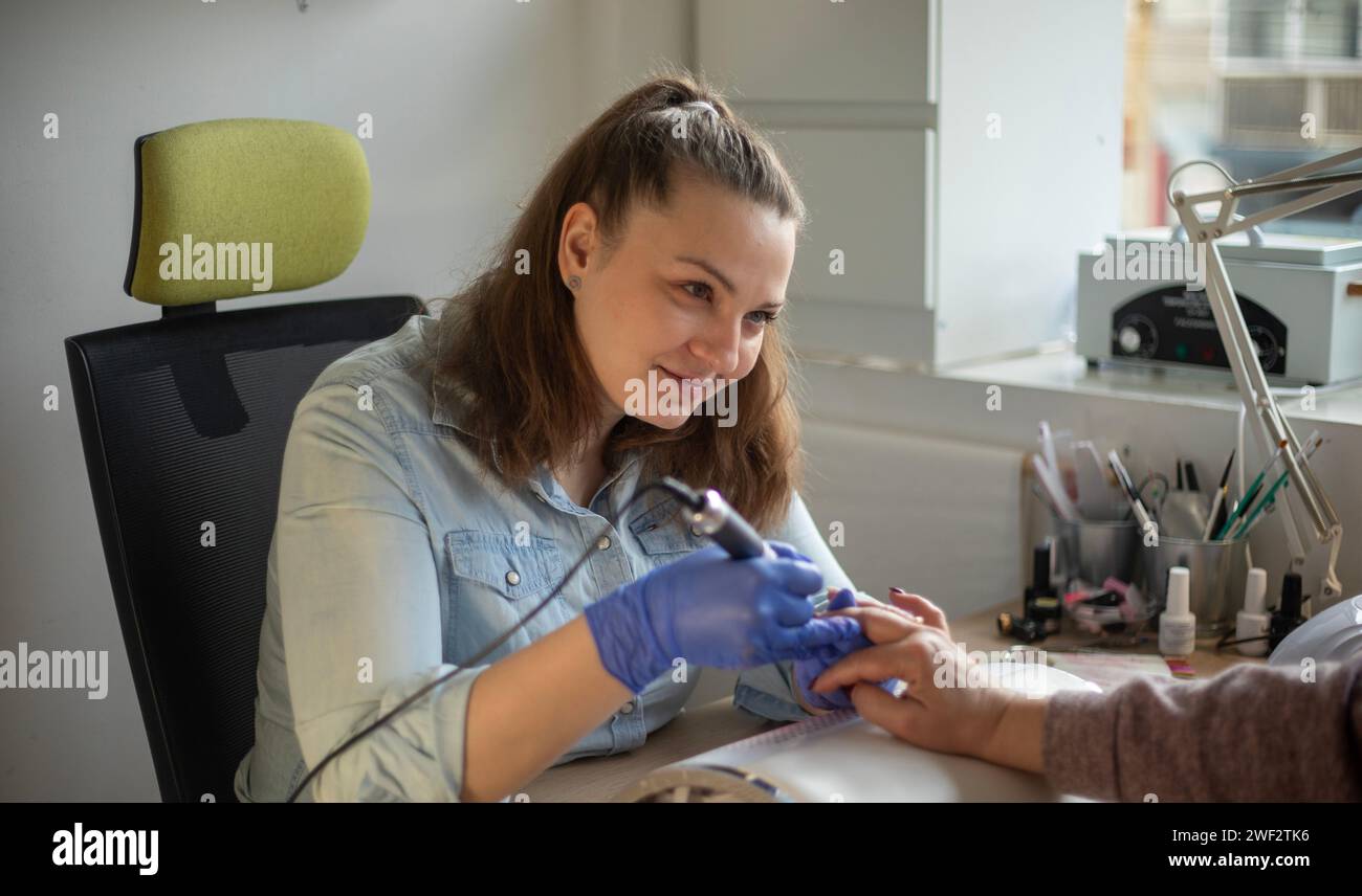 Nail technician smiling back at unrecognisable client, Manicurist happy ...