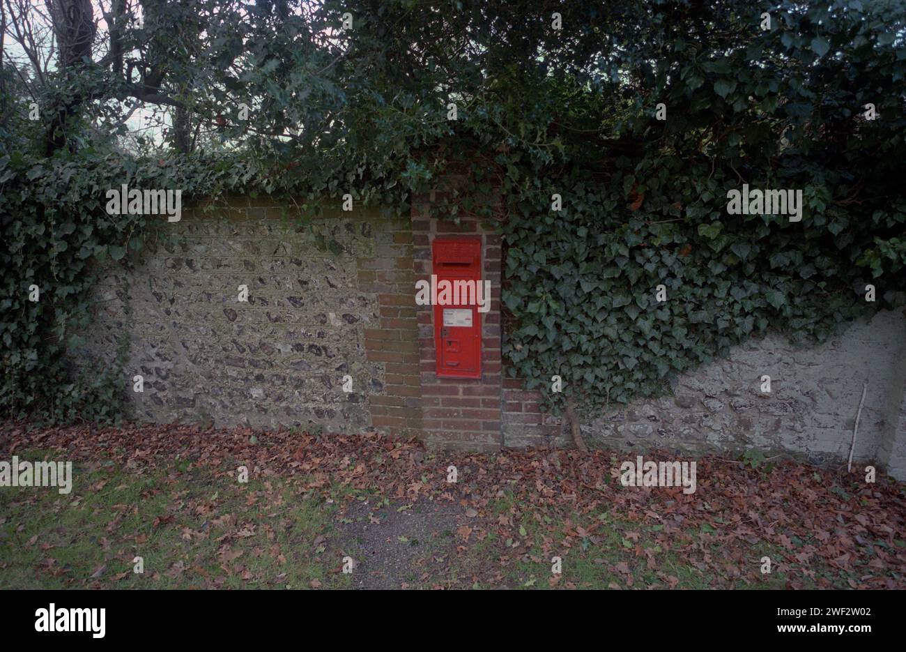 A Royal Mail red post box built in a wall iwith ivy surround n the ...