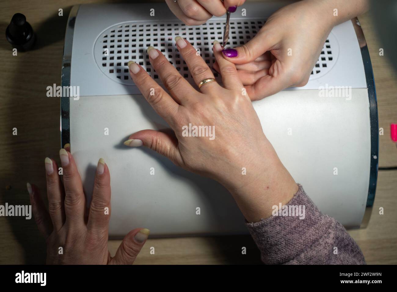 Closeup of manicurist with tool pushing cuticle of her customer. Nail ...