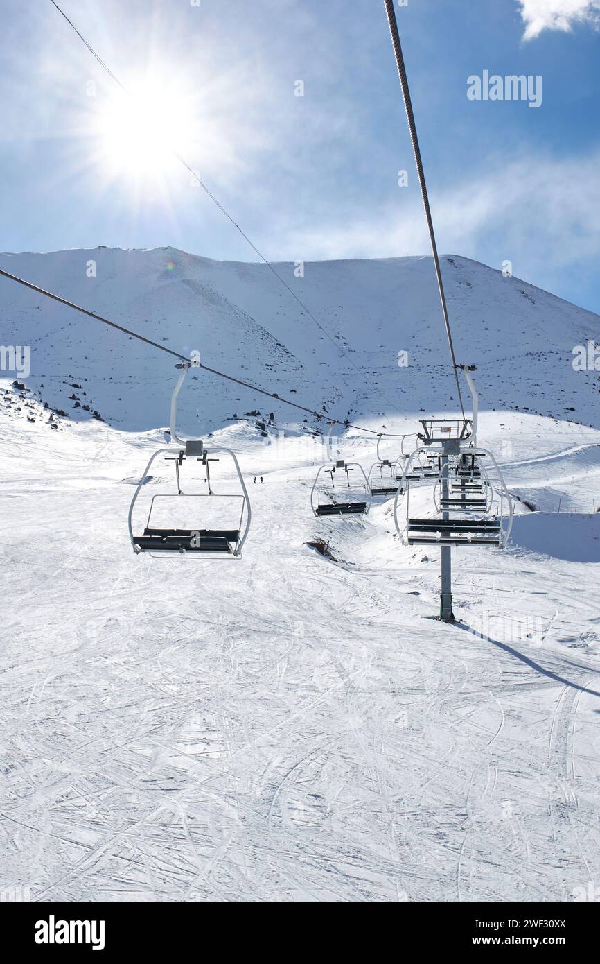 Ski lift with empty chairs at winter resort. Sunny day, blue sky. Snowy ...