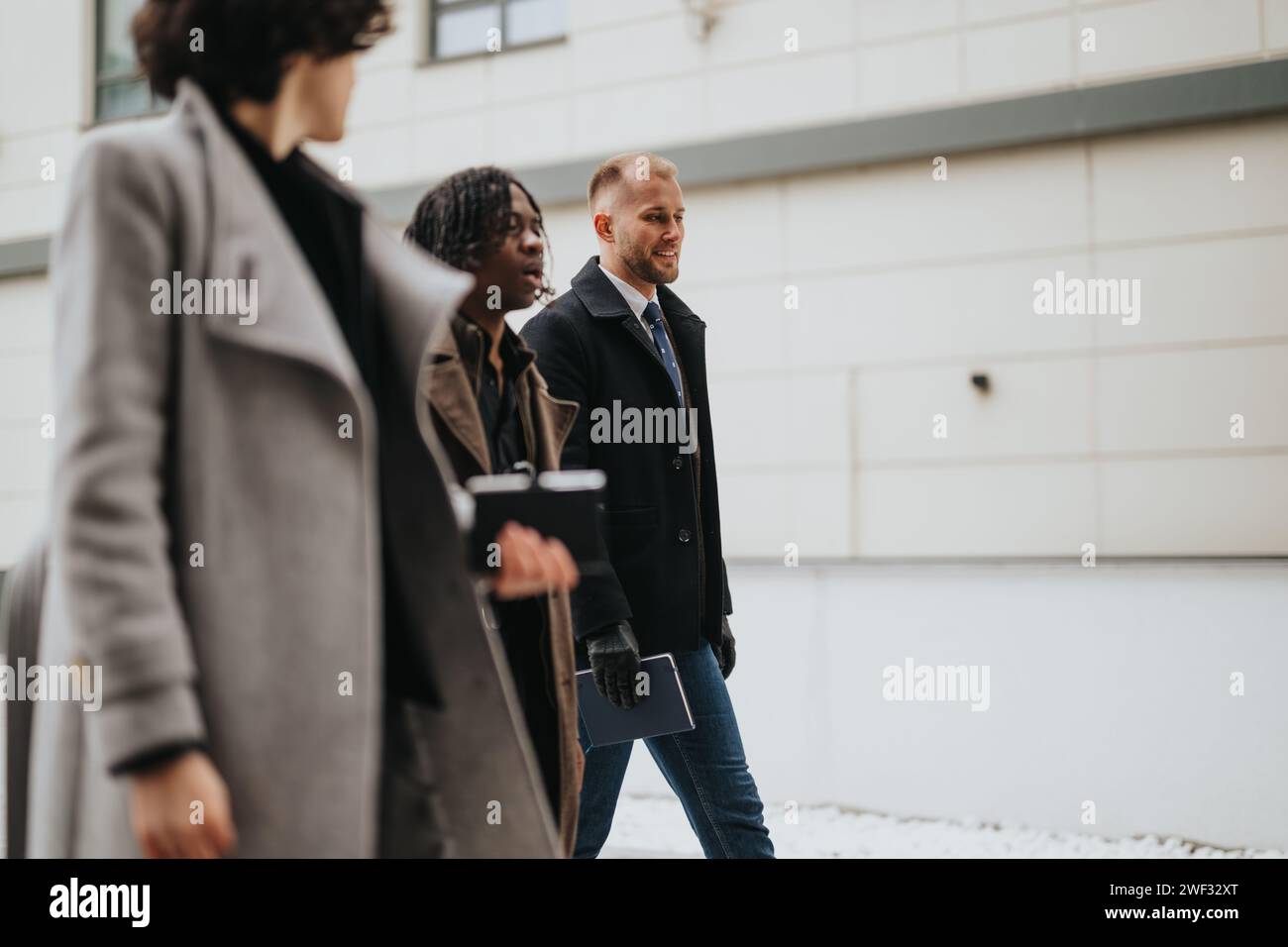 Three happy colleagues in stylish winter attire enjoying a light moment ...
