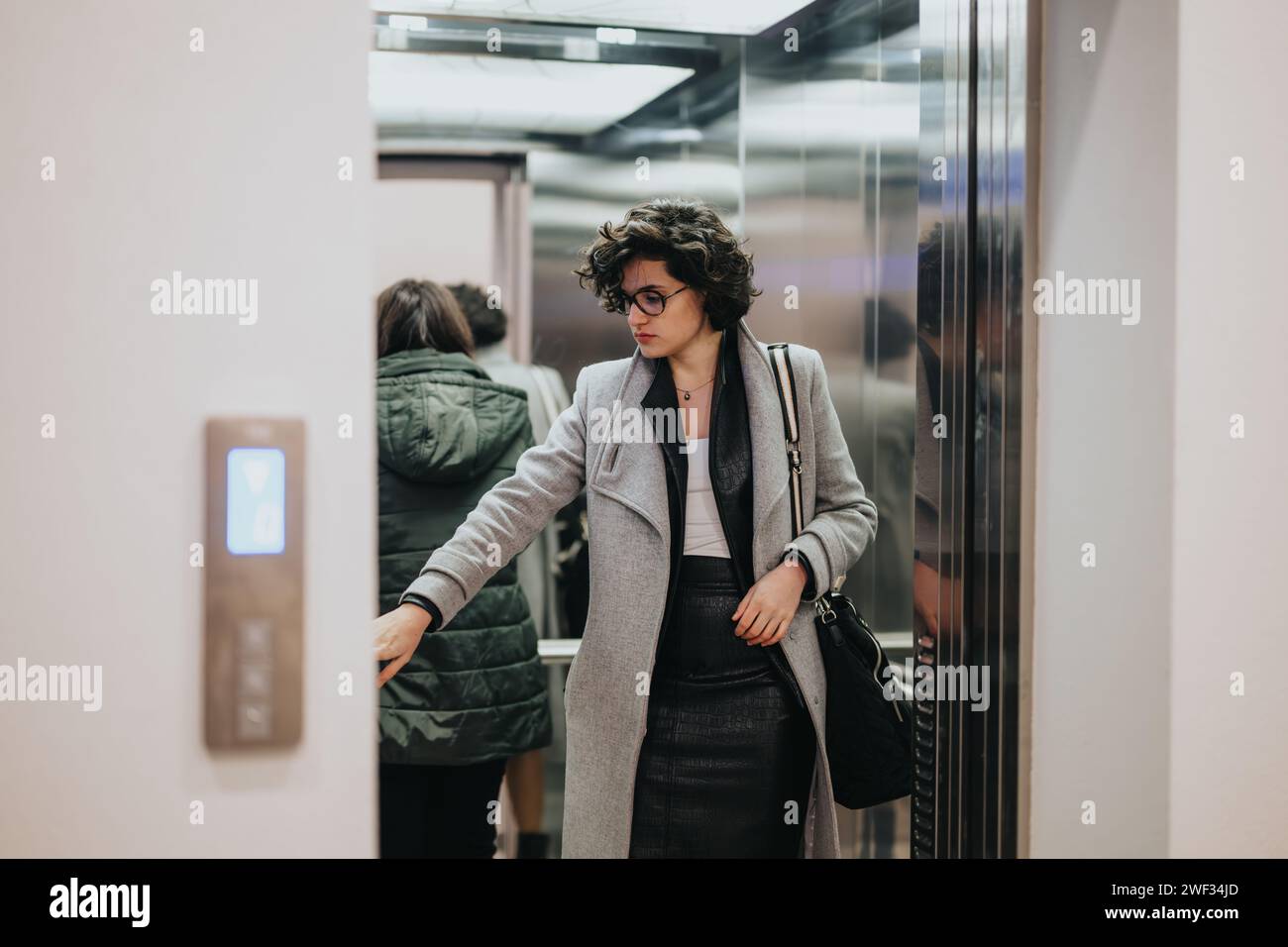 Professional woman pressing elevator button in modern office building ...