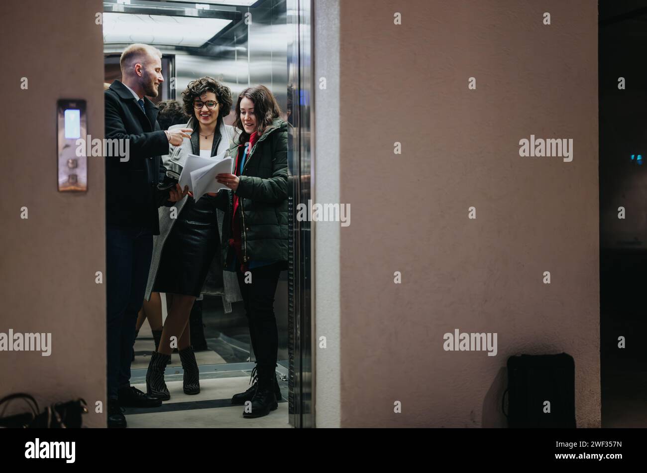 Colleagues reviewing documents in elevator: Urban office building scene ...