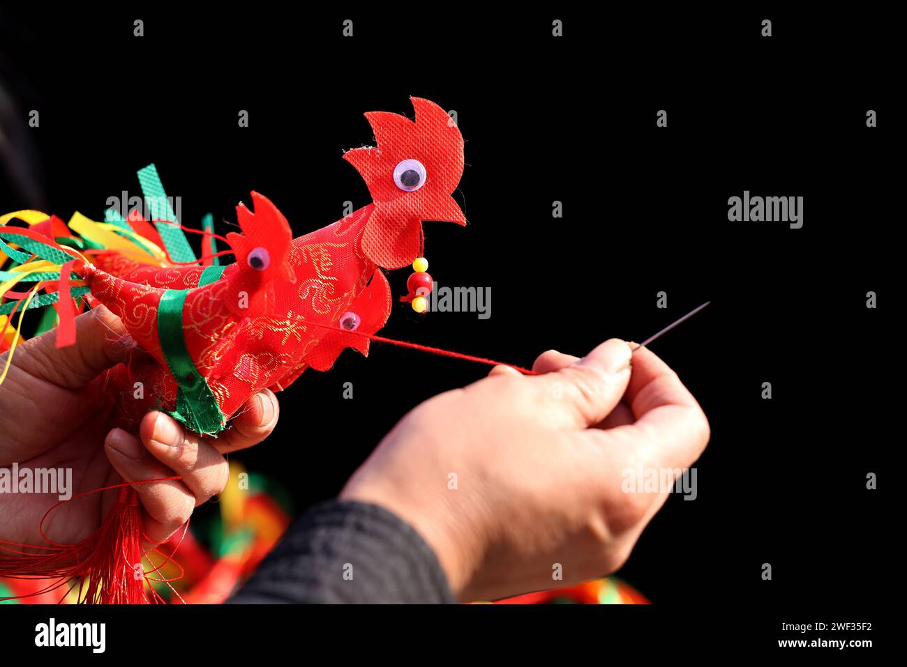 A folk artist is sewing a ''Spring chicken'' at a New Year shopping ...