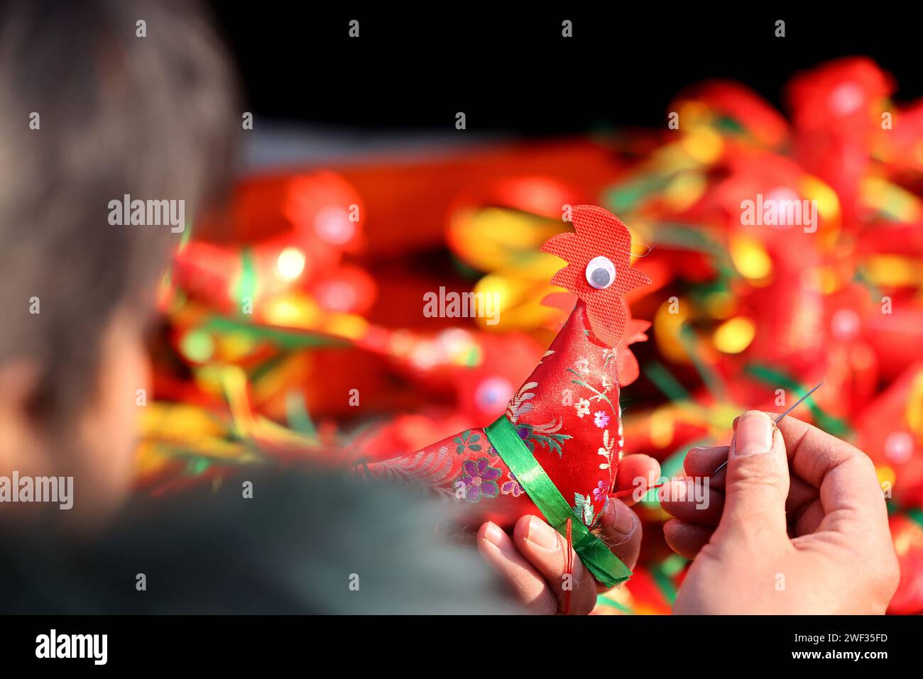 A folk artist is sewing a ''Spring chicken'' at a New Year shopping ...