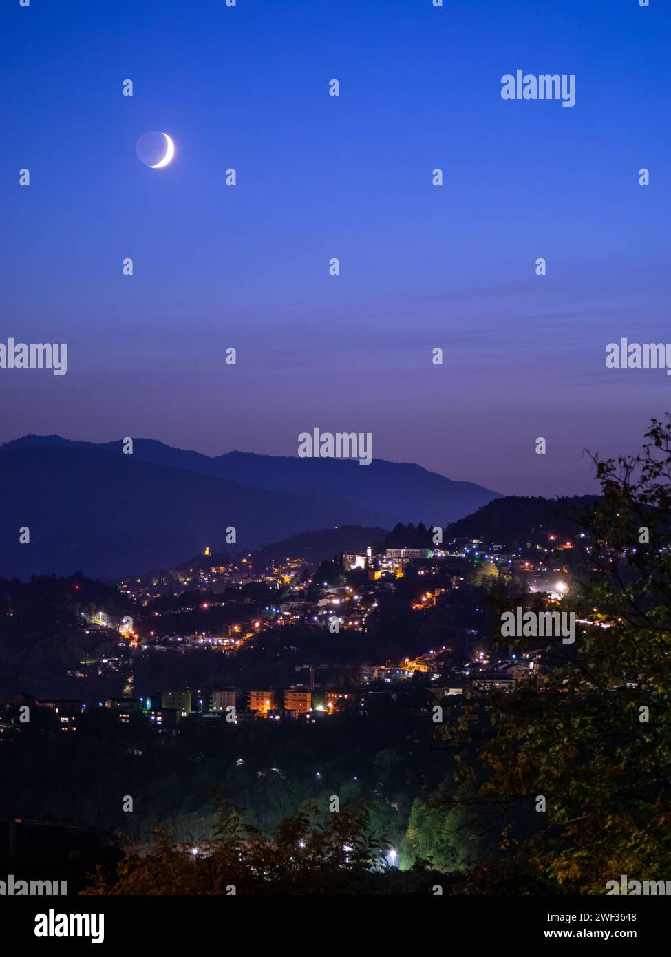 Moon and night sky over town from hilltop Stock Photo - Alamy