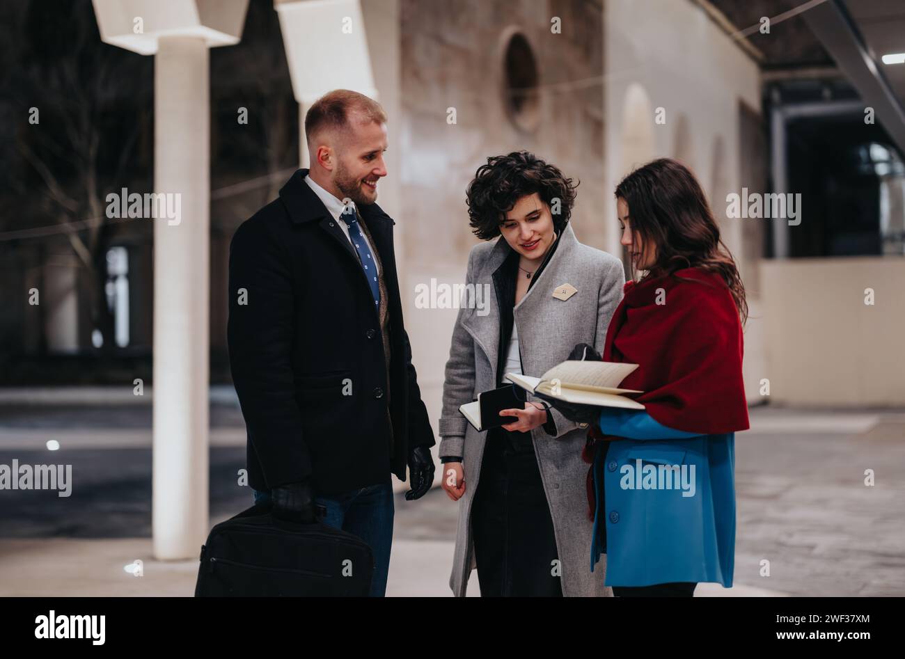 Three business professionals sharing ideas outdoors with notebook and ...