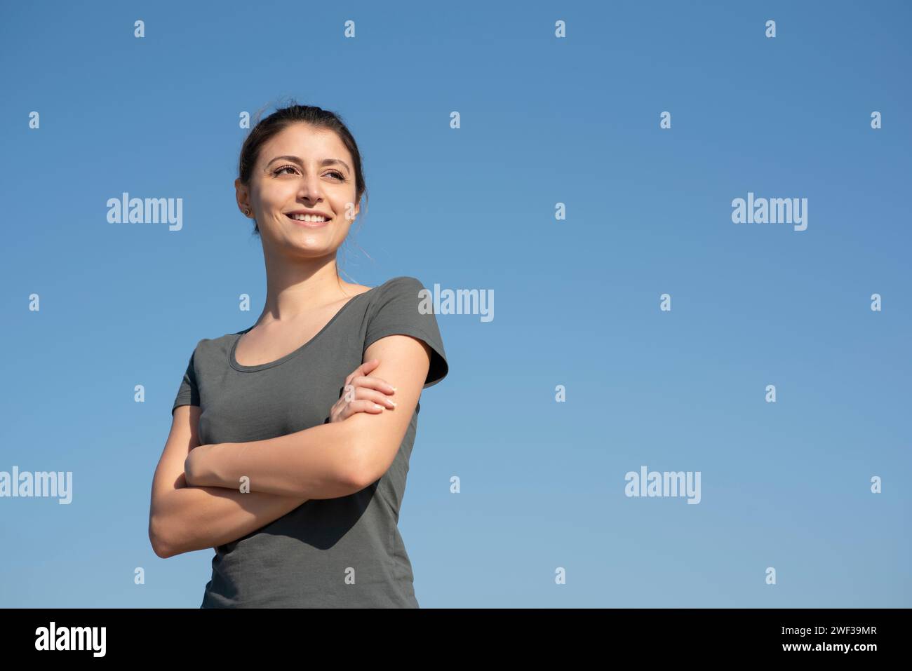 Beautiful woman arms folded looking away smiling outdoors Stock Photo ...