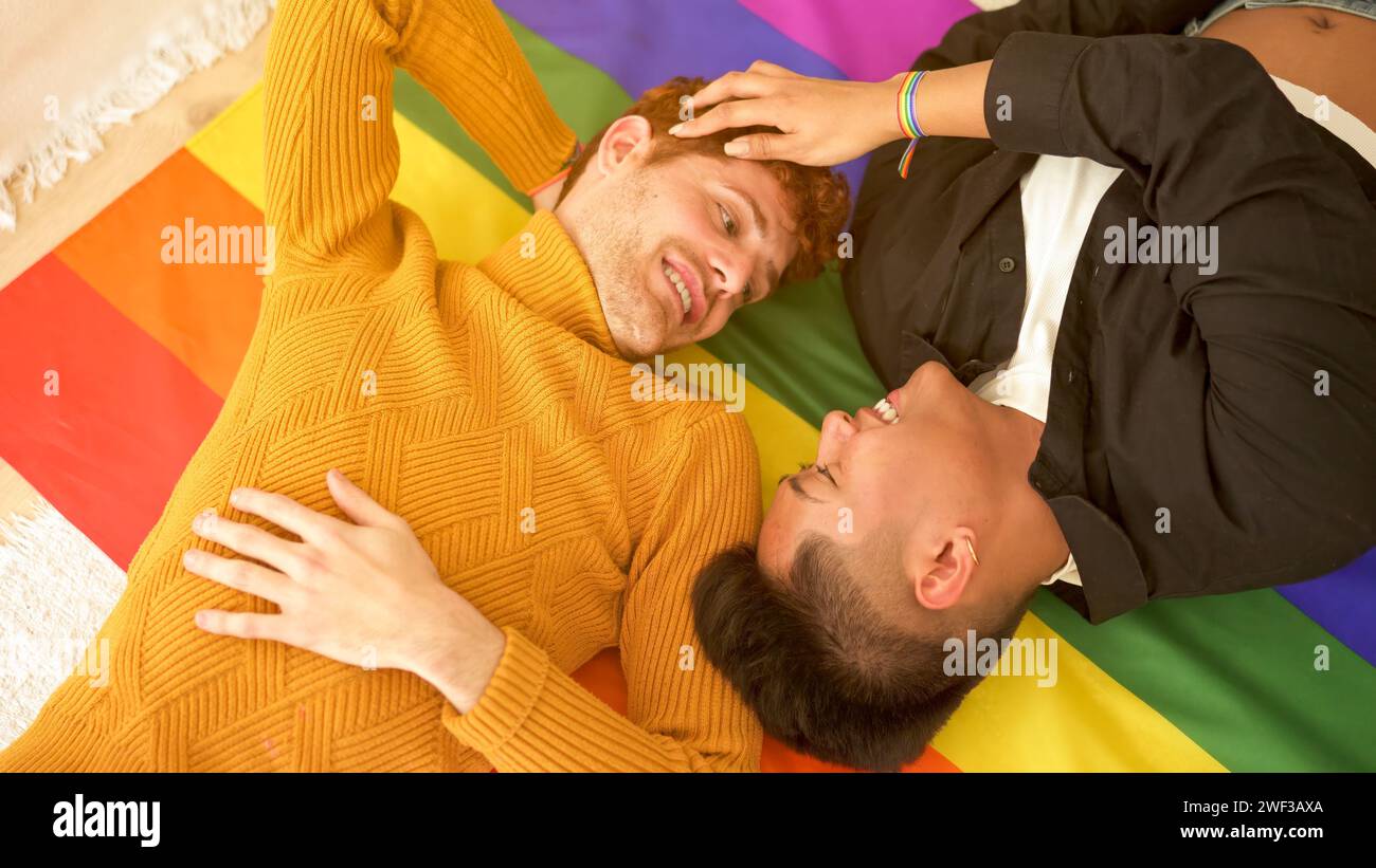 Happy gay couple lying on top of a lgbt flag Stock Photo - Alamy