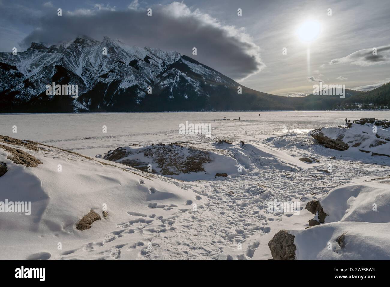 Sun over frozen Lake Minnewanka in Banff National Park, Alberta, Canada ...