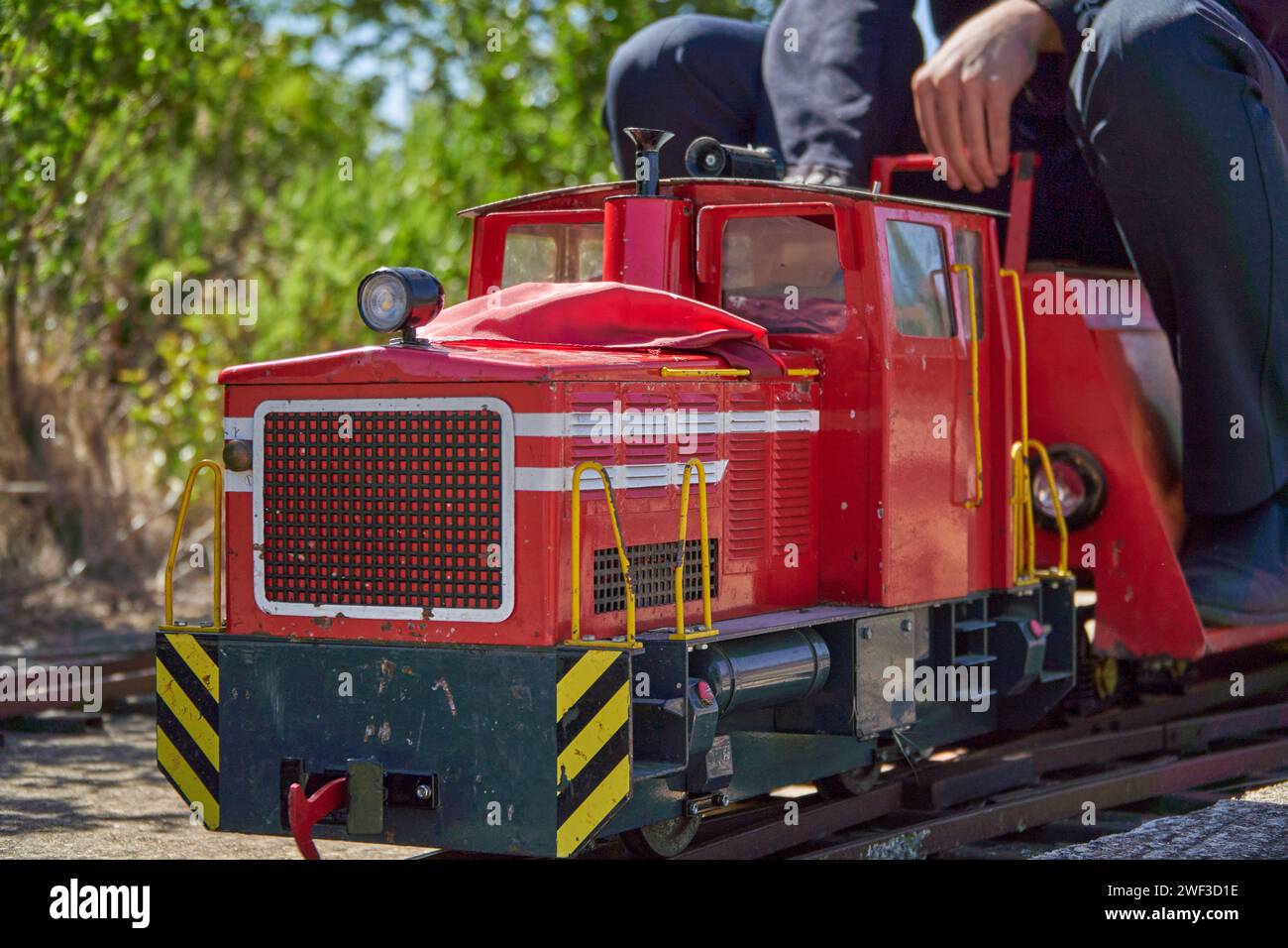 Young adult with railway station master uniform riding a toy train of 5 ...