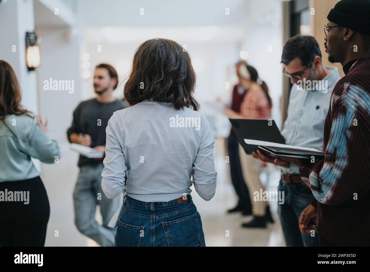 Multicultural group of people collaborating and using laptops in a bright, contemporary office ...