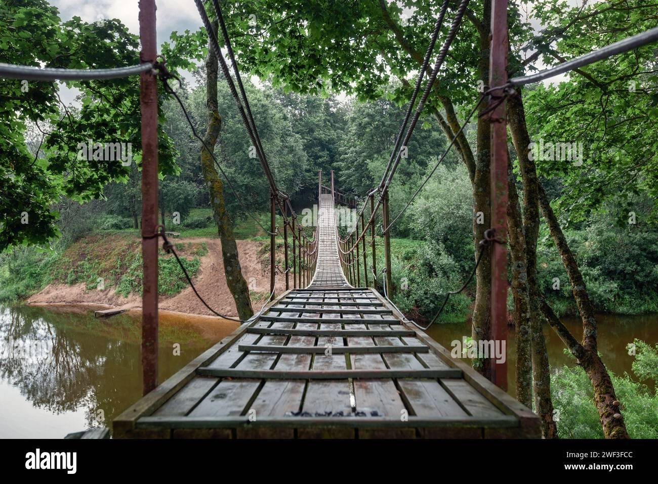 Hanging monkey bridge over the Minija river in Lithuania. Shot from a ...