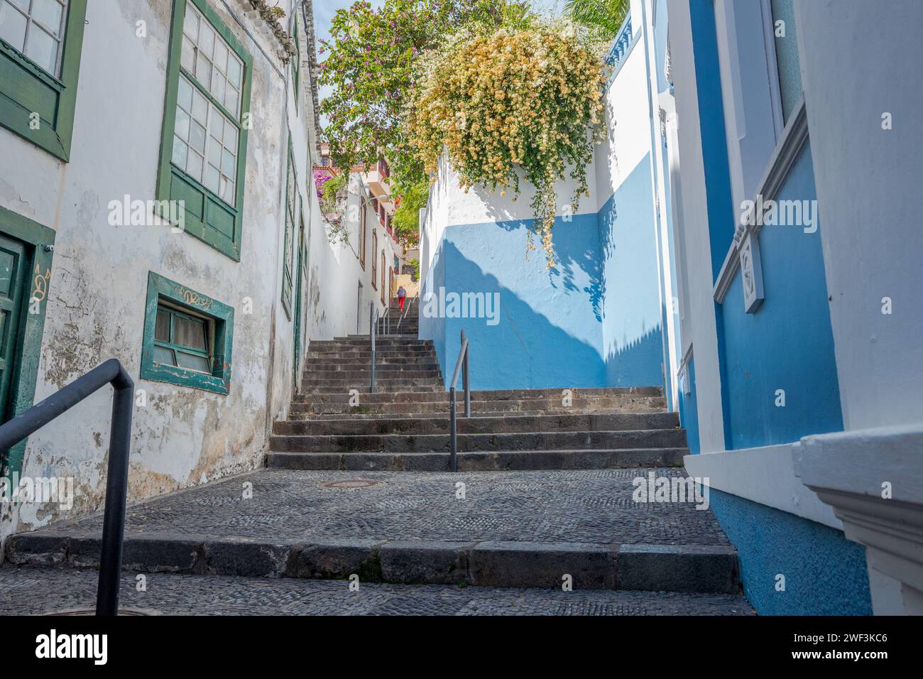 Narrow passage between white painted rendered buildings with steep ...