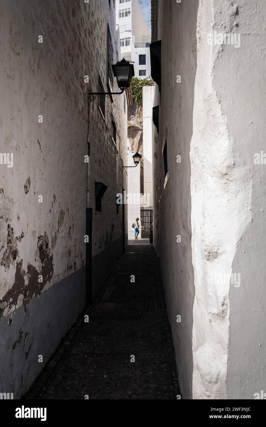 Narrow passage between white painted rendered buildings with person ...