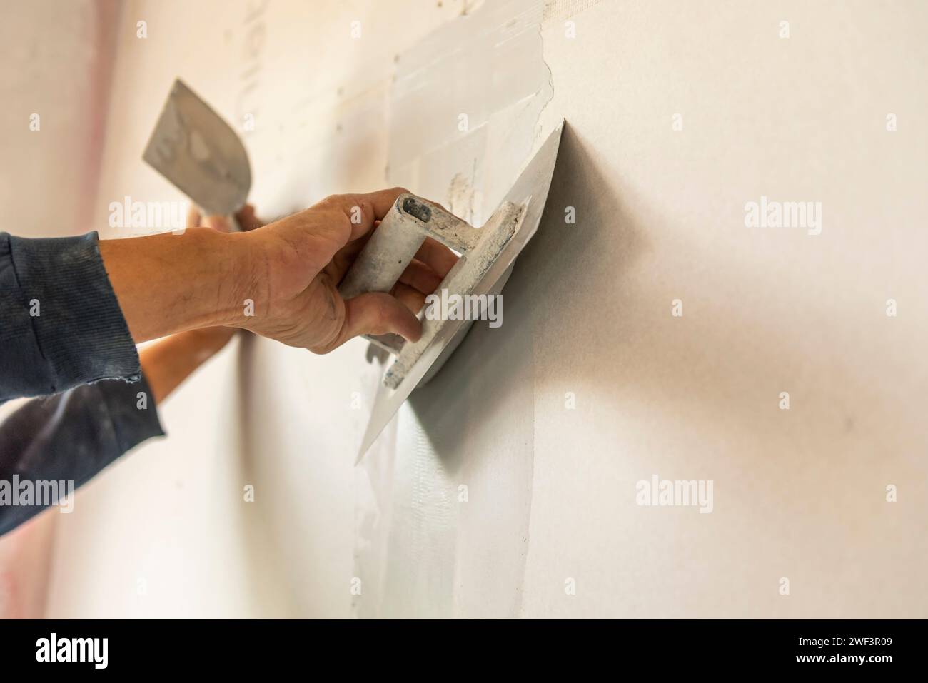 old manual worker with wall plastering tools renovating house ...