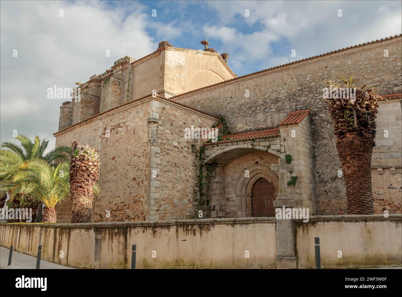 Sand coloured stone ancient building with palm trees behind a wall ...