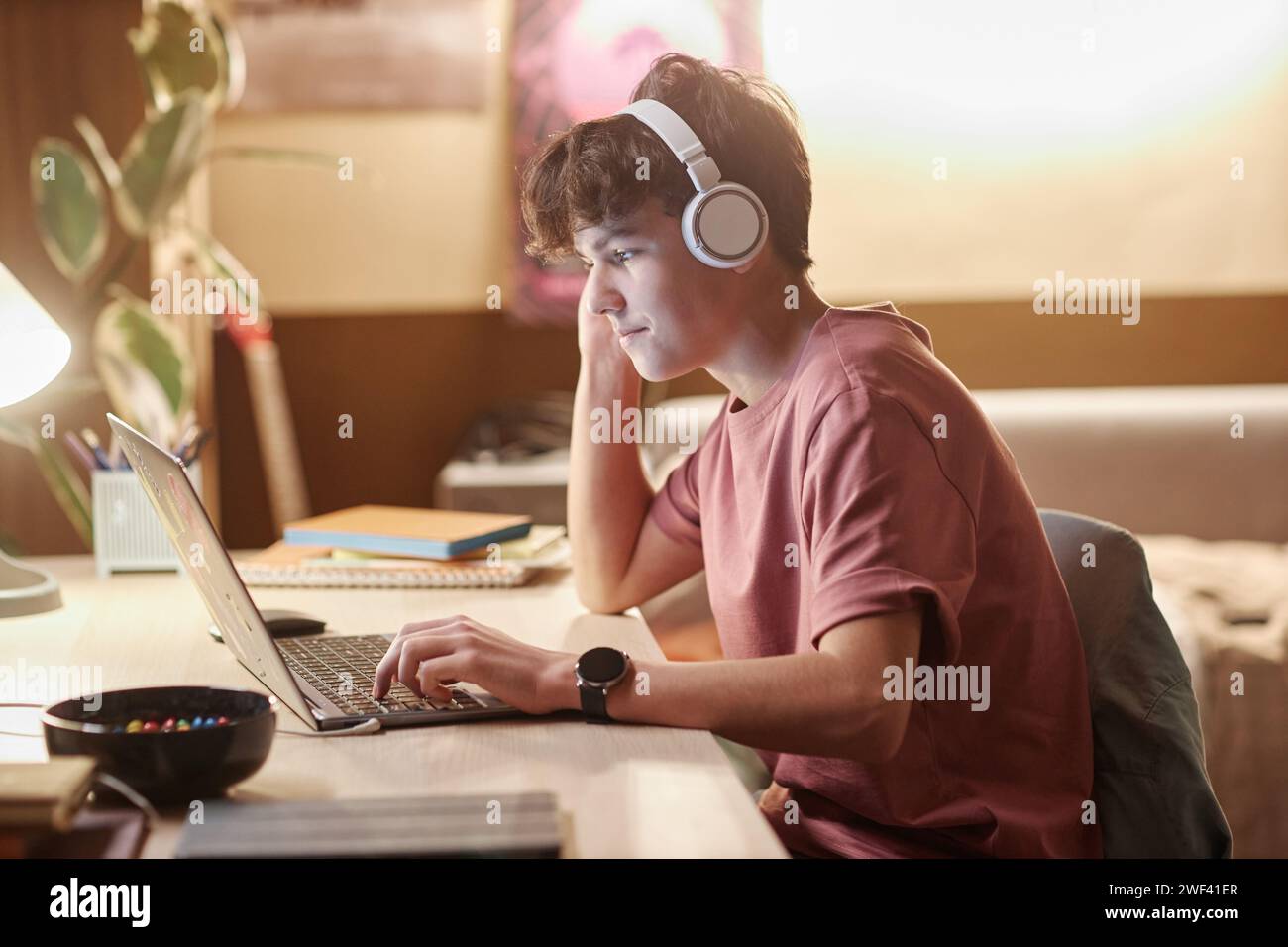 Side view portrait of teenage boy using laptop at night with wireless ...