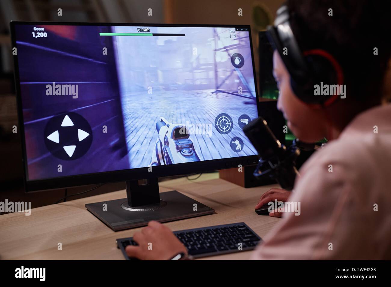 Back view of African American teenage girl playing video games on PC ...