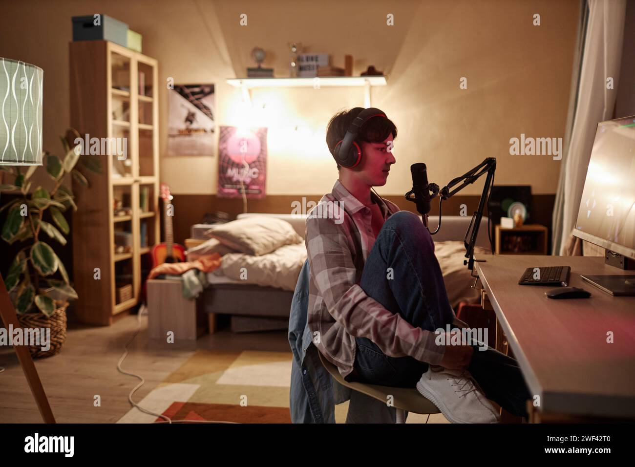 Wide angle side view of teenage boy speaking to microphone while live ...