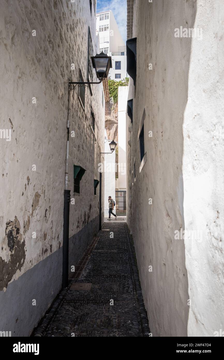 Narrow passage between white painted rendered buildings with person ...