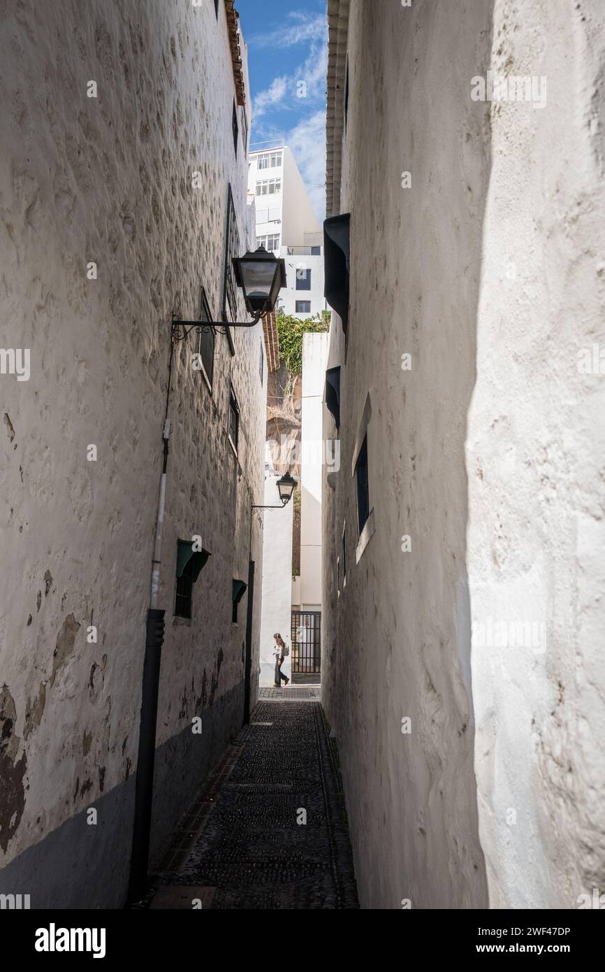 Narrow passage between white painted rendered buildings with person ...