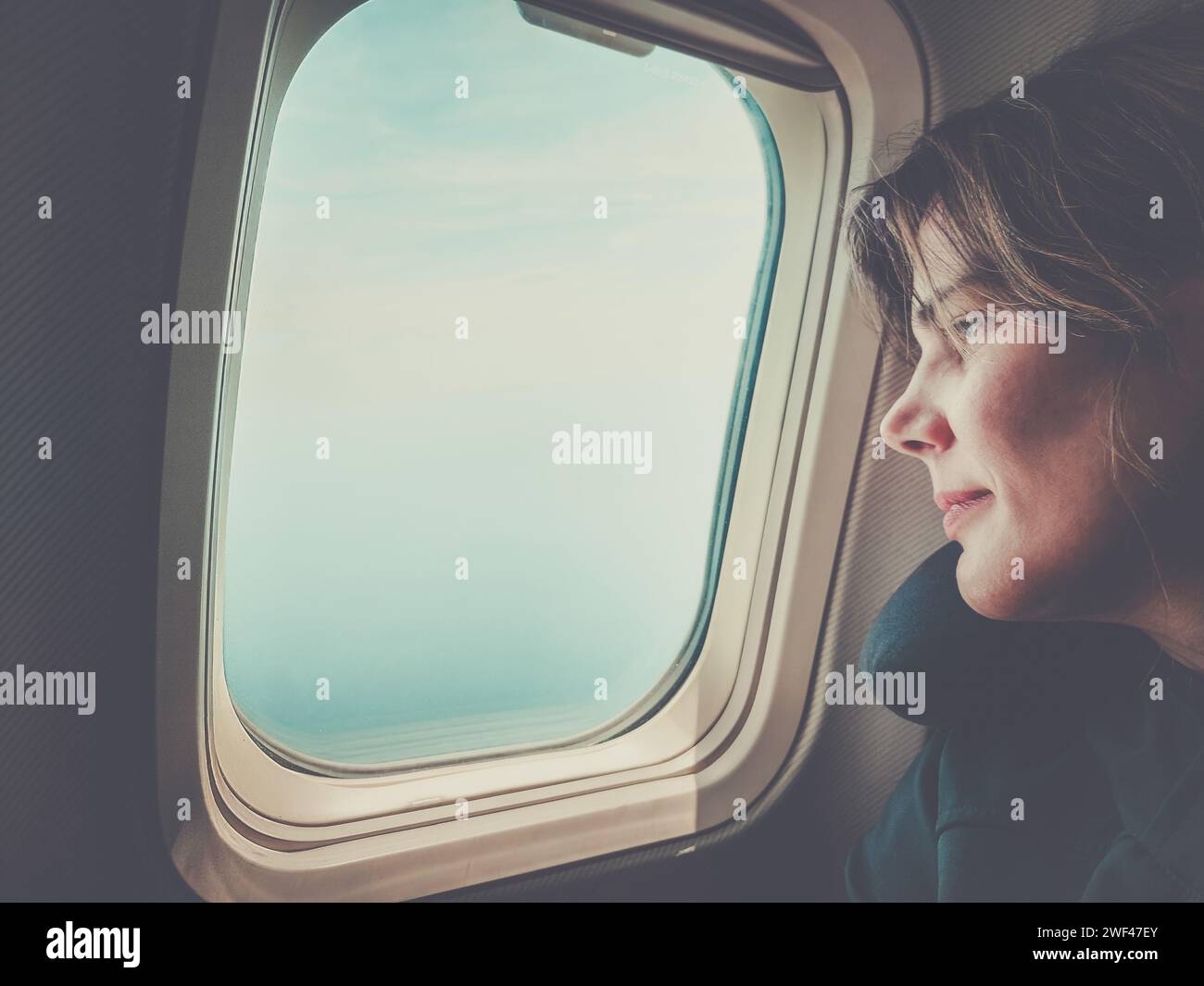 Beautiful girl looks out the window of the airplane. Summer vacation ...