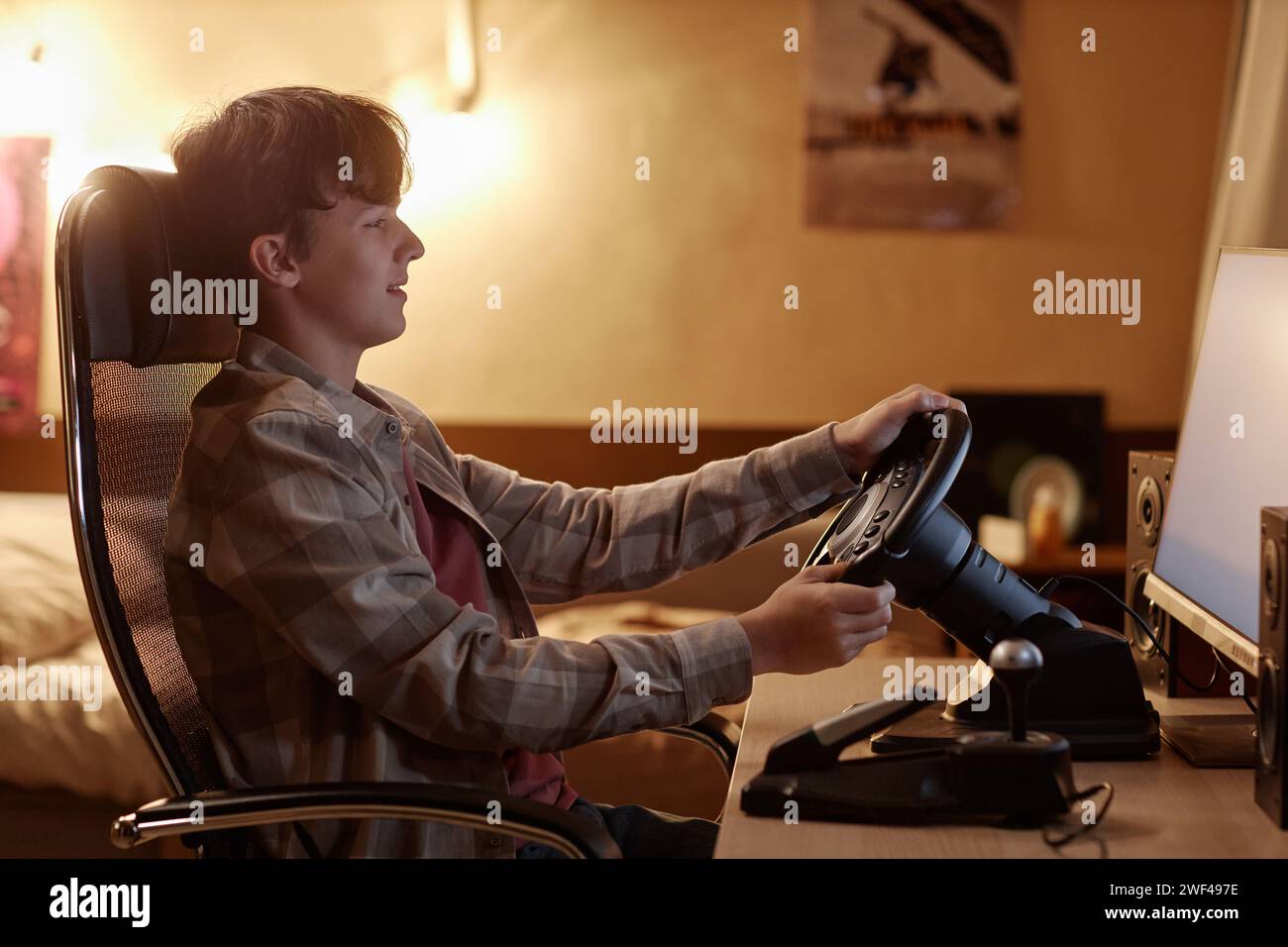 Side view of teen boy playing racing simulator video game and turning ...