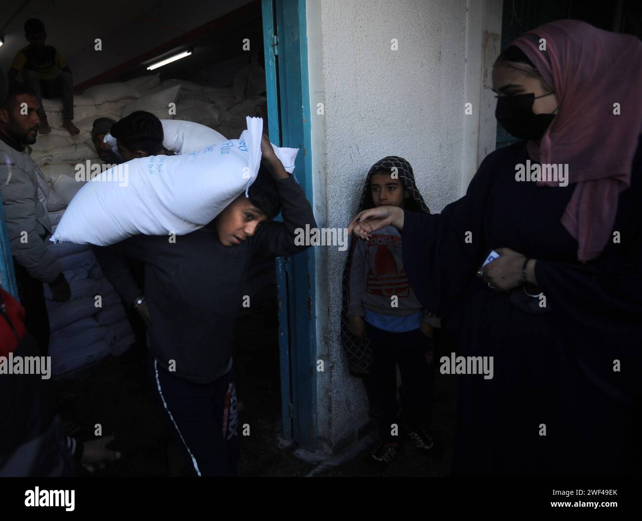 Displaced Palestinians receive bags of flour at the United Nations ...