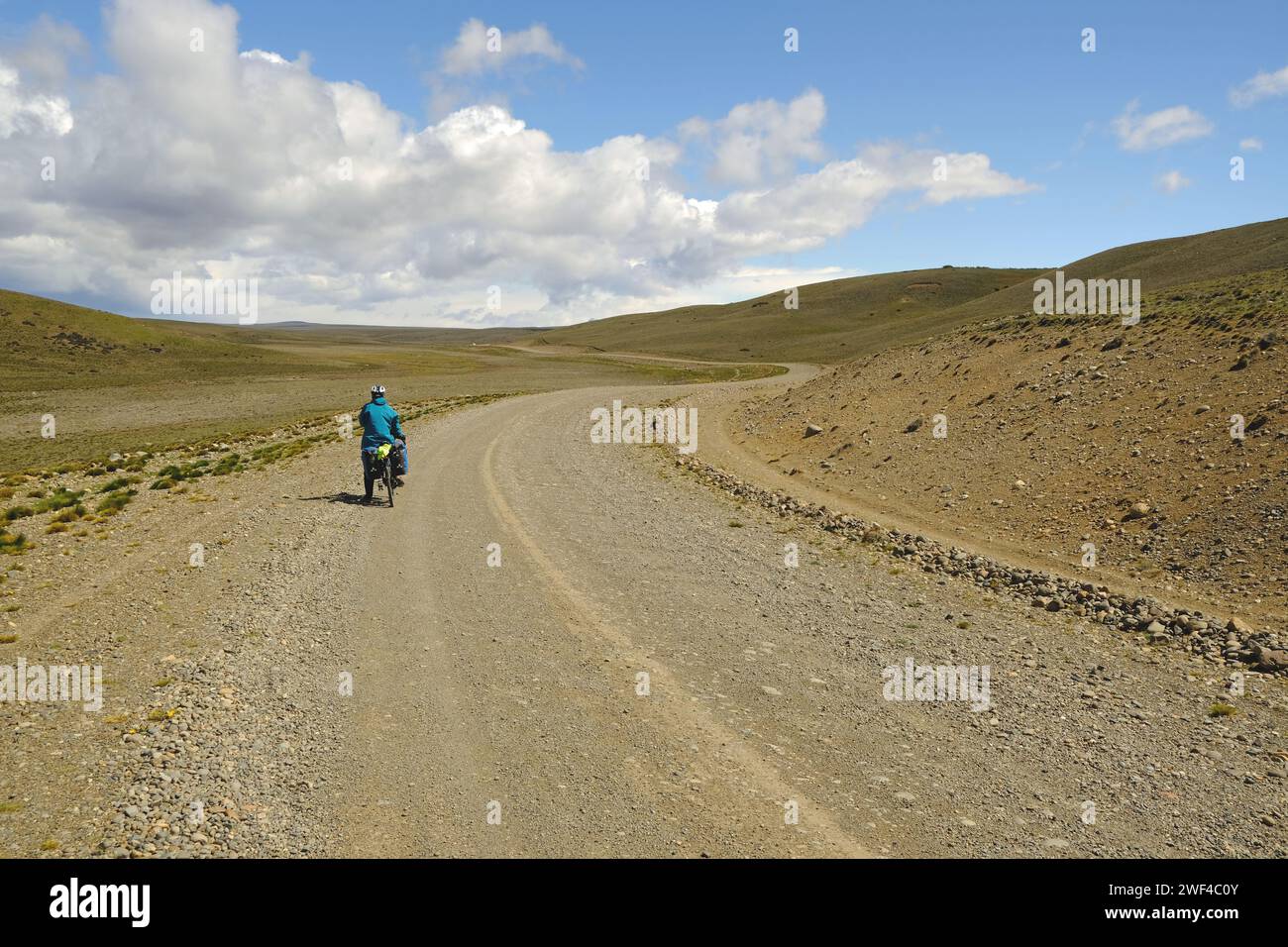 Cyclist on a rough gravel road which weaves through the Argentine pampa ...
