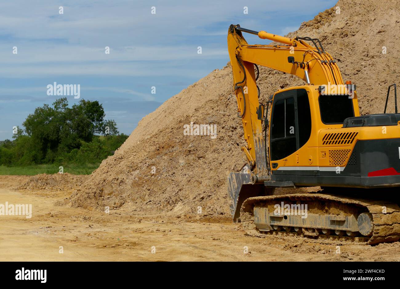 An excavator car and a pile of dirt in a road construction area in a ...