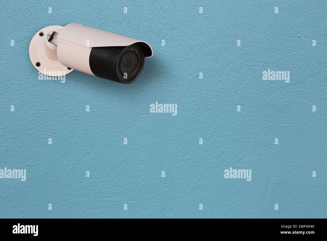 White CCTV camera system mounted on light blue wall of blue cement wall ...