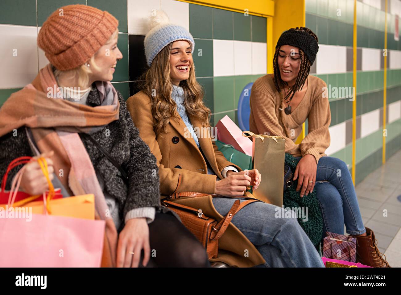 Three fashionable friends with shopping bags laugh together while ...