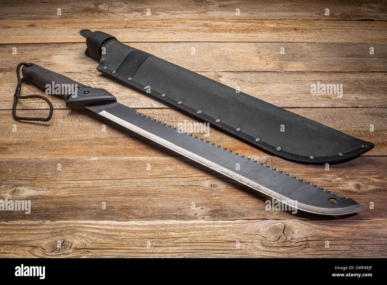 bush clearing machete with carbon steel blade and saw against rustic ...