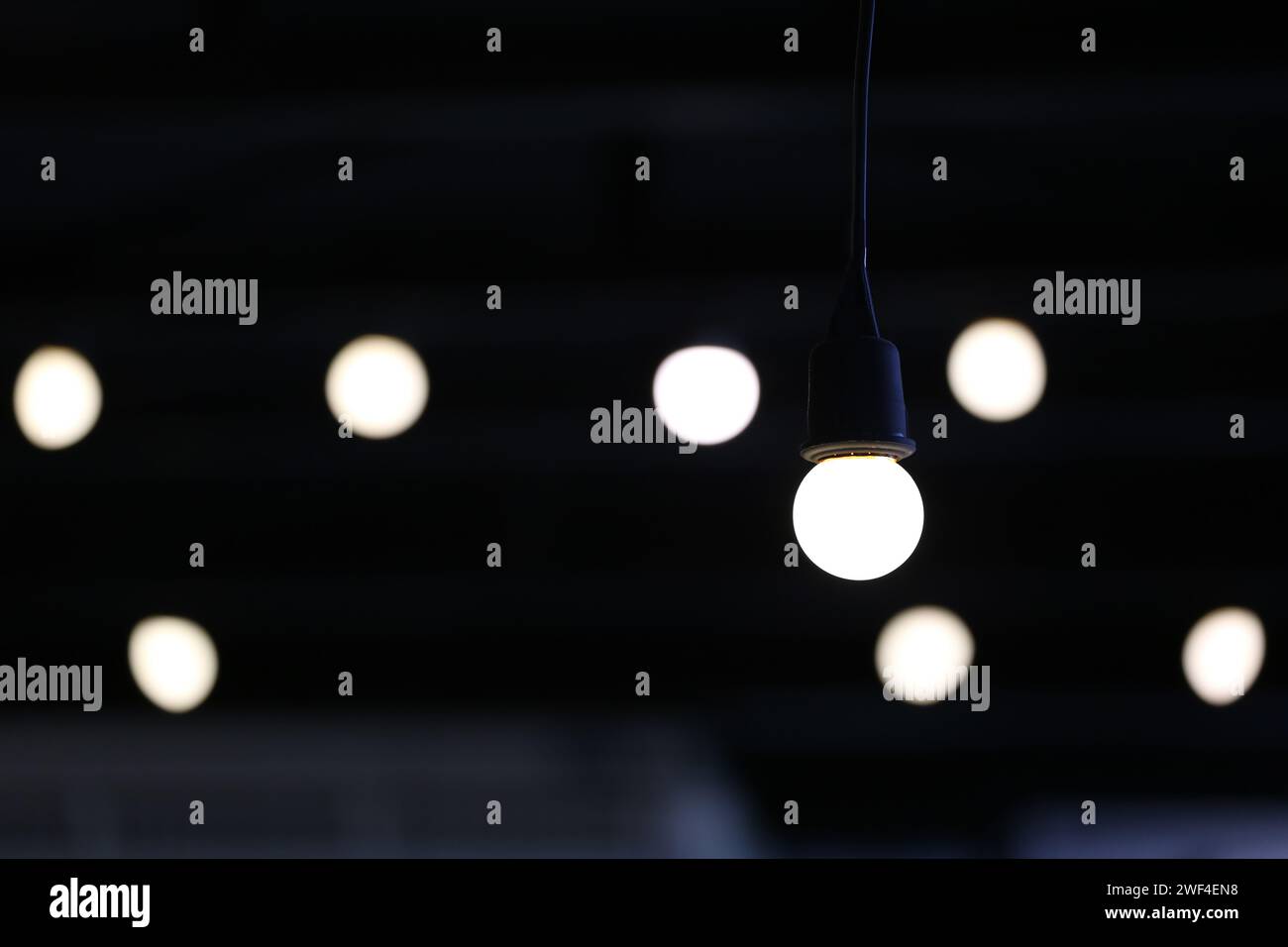 Small light bulb that is on and a blurred bulb of lights in a black ...