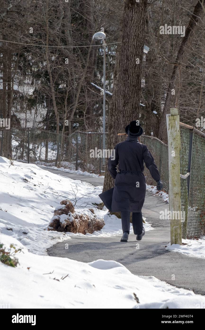 An unidentified orthodox Jewish man dressed in black walks on a winding ...