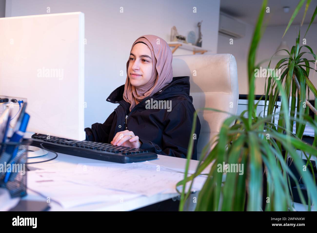Muslim female working in office using computer with white background ...
