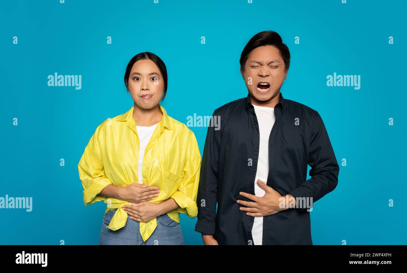 Concerned young woman with hands clasped while a man beside her winces ...