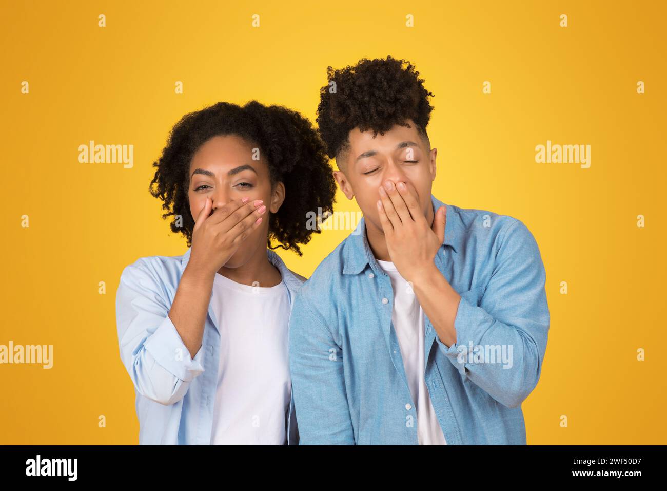 Shocked young African American woman and man with hands over one eye ...