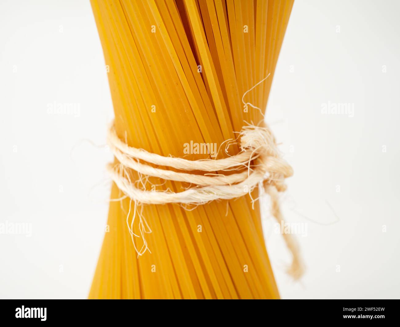 Spaghetti tied with rope on a white background. Raw spaghetti close-up ...