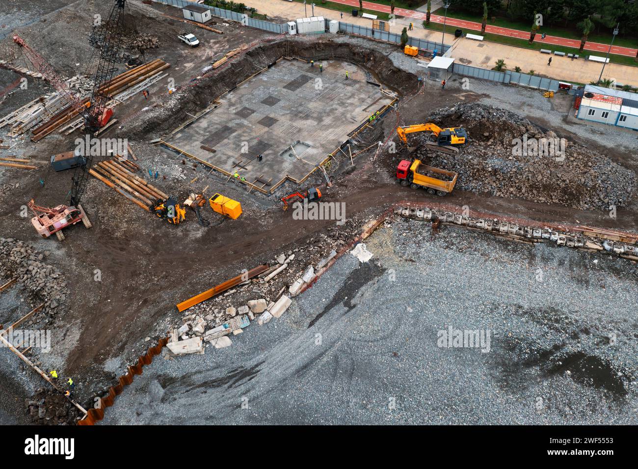 Aerial view of construction site with excavators and dump trucks during earthworks and building ...