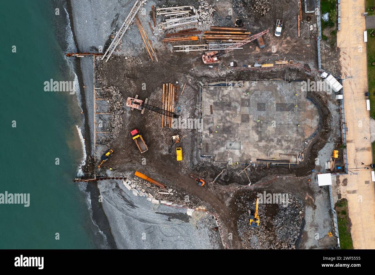 Aerial top down view of construction site with excavators and dump trucks during earthworks and ...
