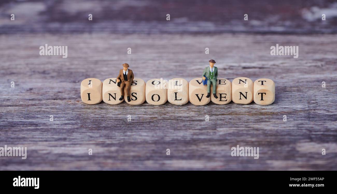 small miniature people in business suit sitting on wooden letters ...