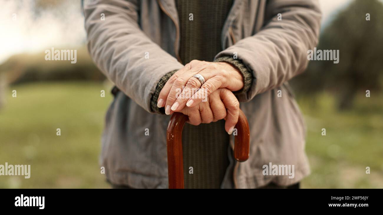 Senior cane, hands and person in nature for walking, relax and in a ...