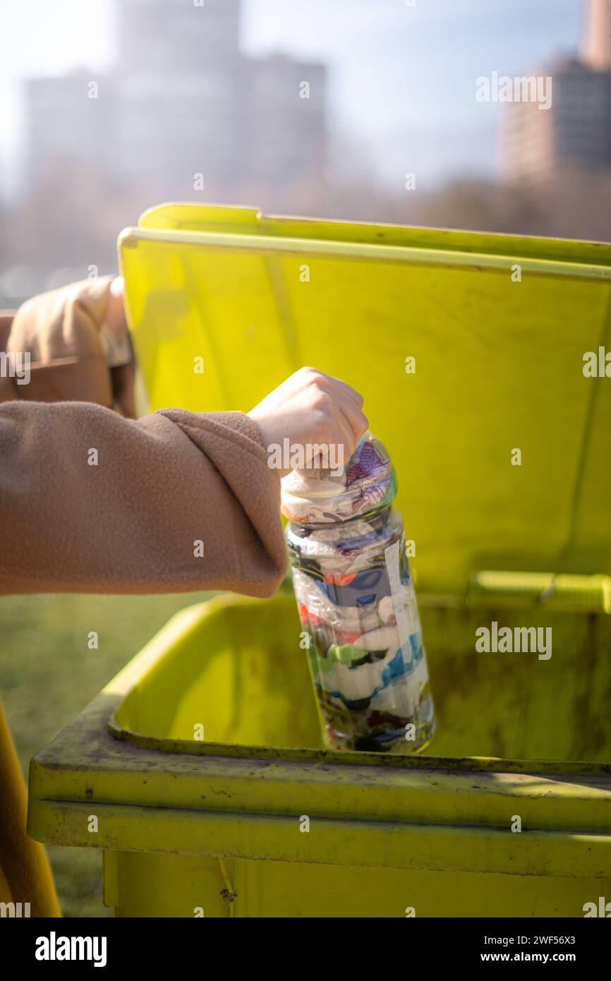 A woman with disability in hand throwing a plastic bottle into green ...