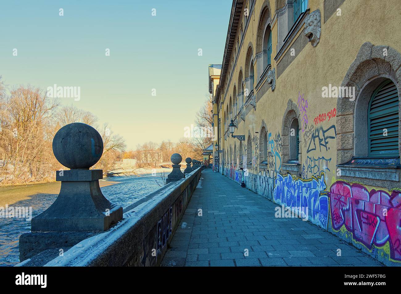 Old heritage building on the river in Munich and a pedestrian foot way ...
